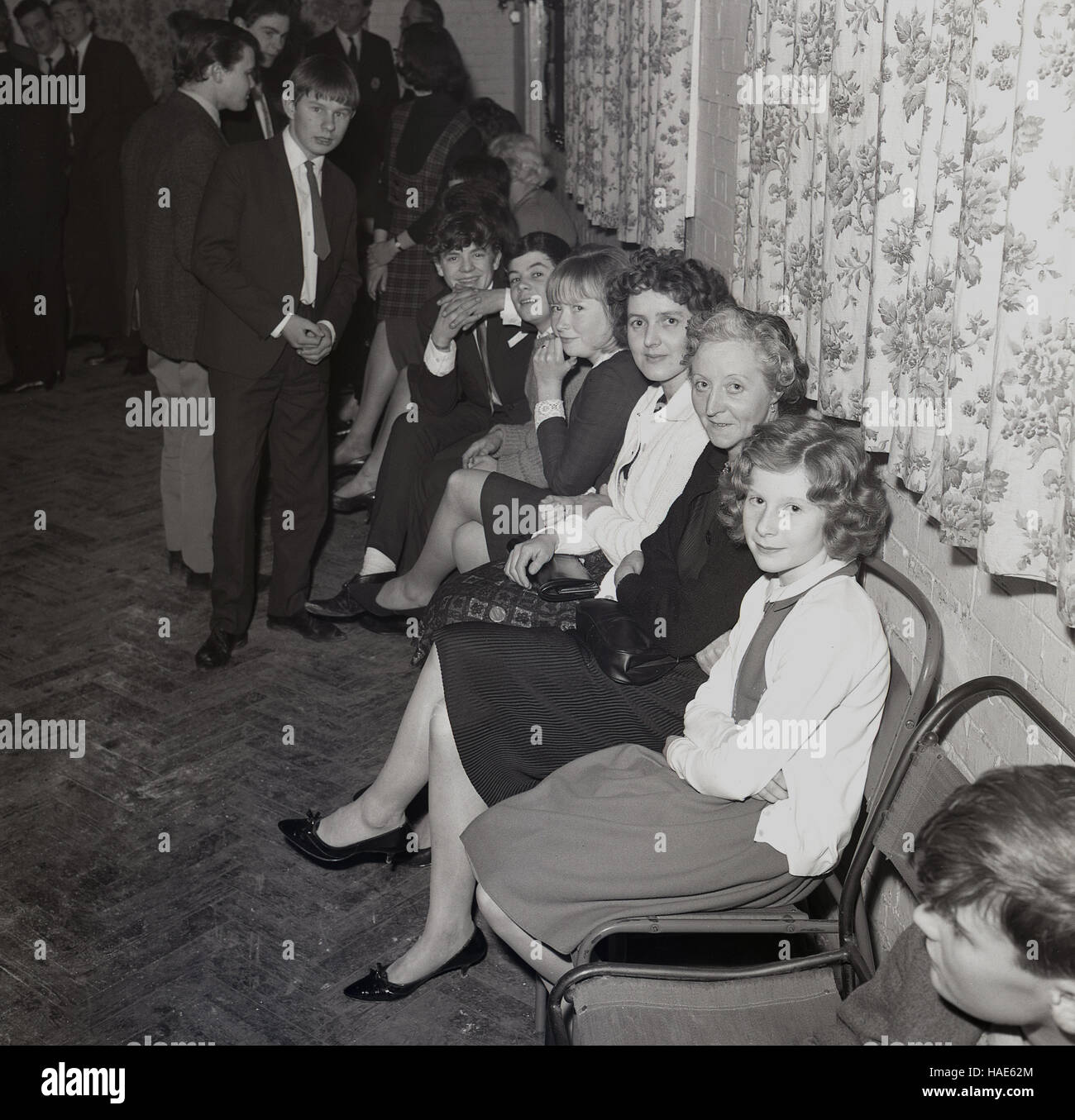 1965, historical, school prom or ball, young girls sitting on metal ...