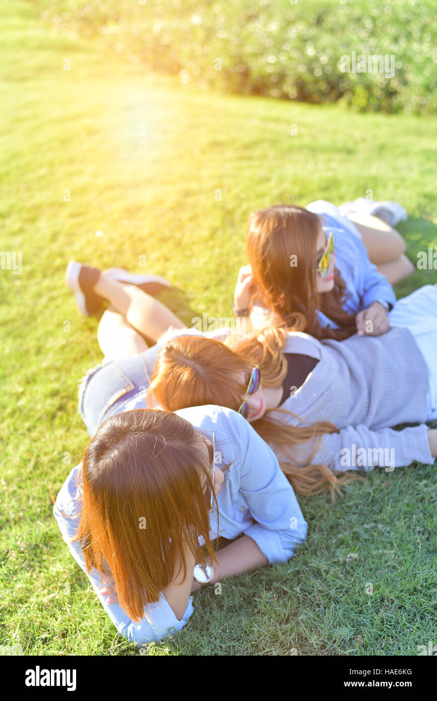 Beautiful Asian Girls Laying On The Green Grass Under Sunlight Wear
