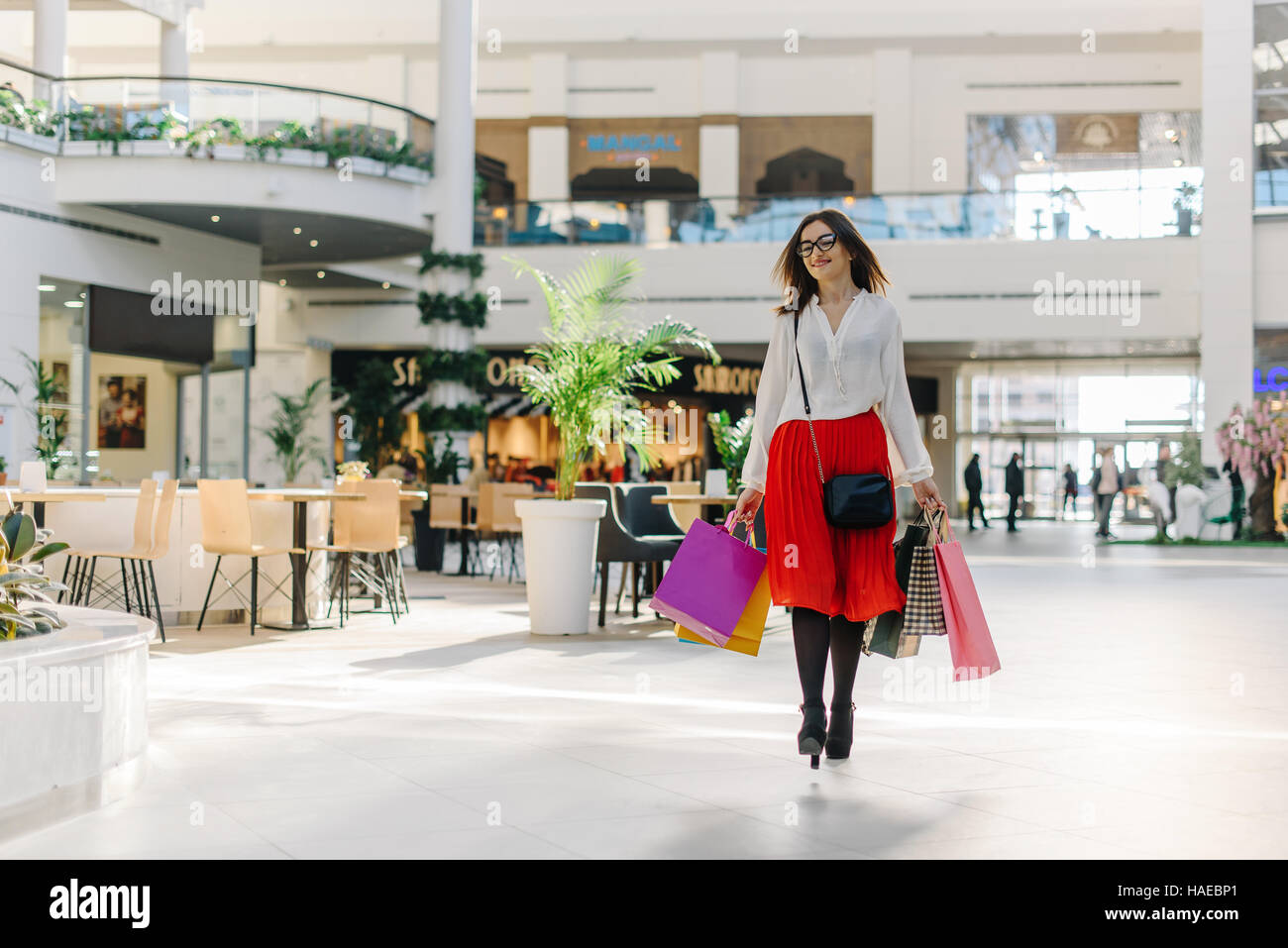 Brunette girl in mall after shopping. Attractive woman wearing midi red ...