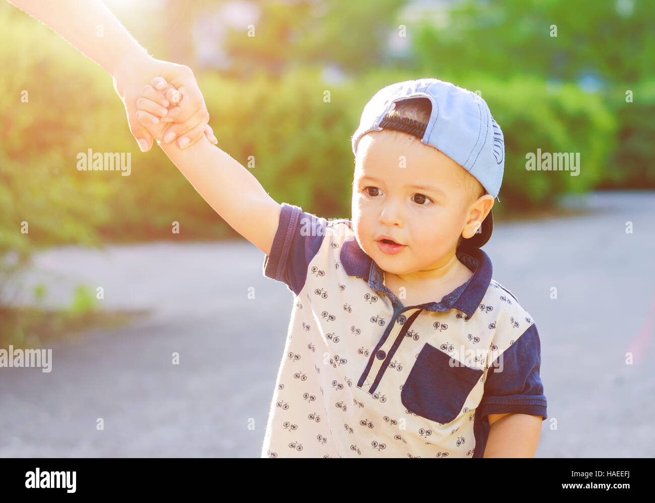 Portrait of a little surprised child in cap walking with her mother on ...