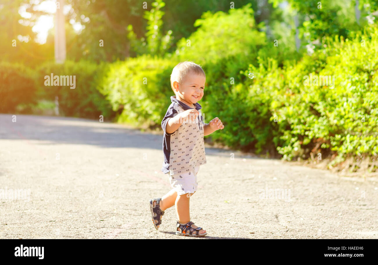 Little boy smiling while walking outdoors on a background of green ...