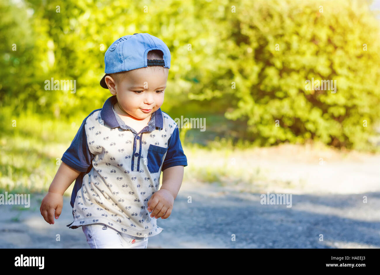 Little boy walking down the street in a blue cap. Summer walk with ...