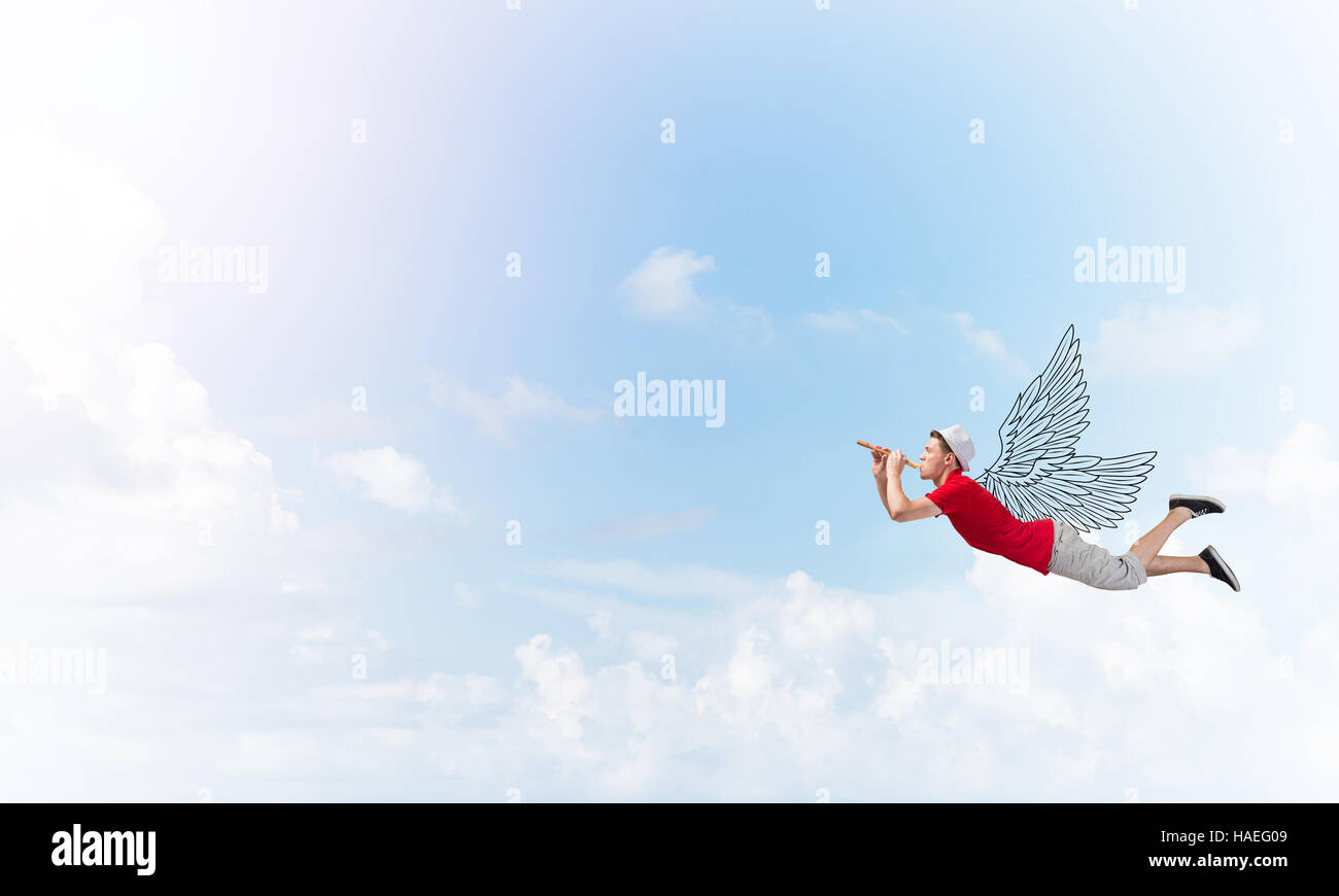 Young cheerful man flying high in sky and playing fife Stock Photo - Alamy