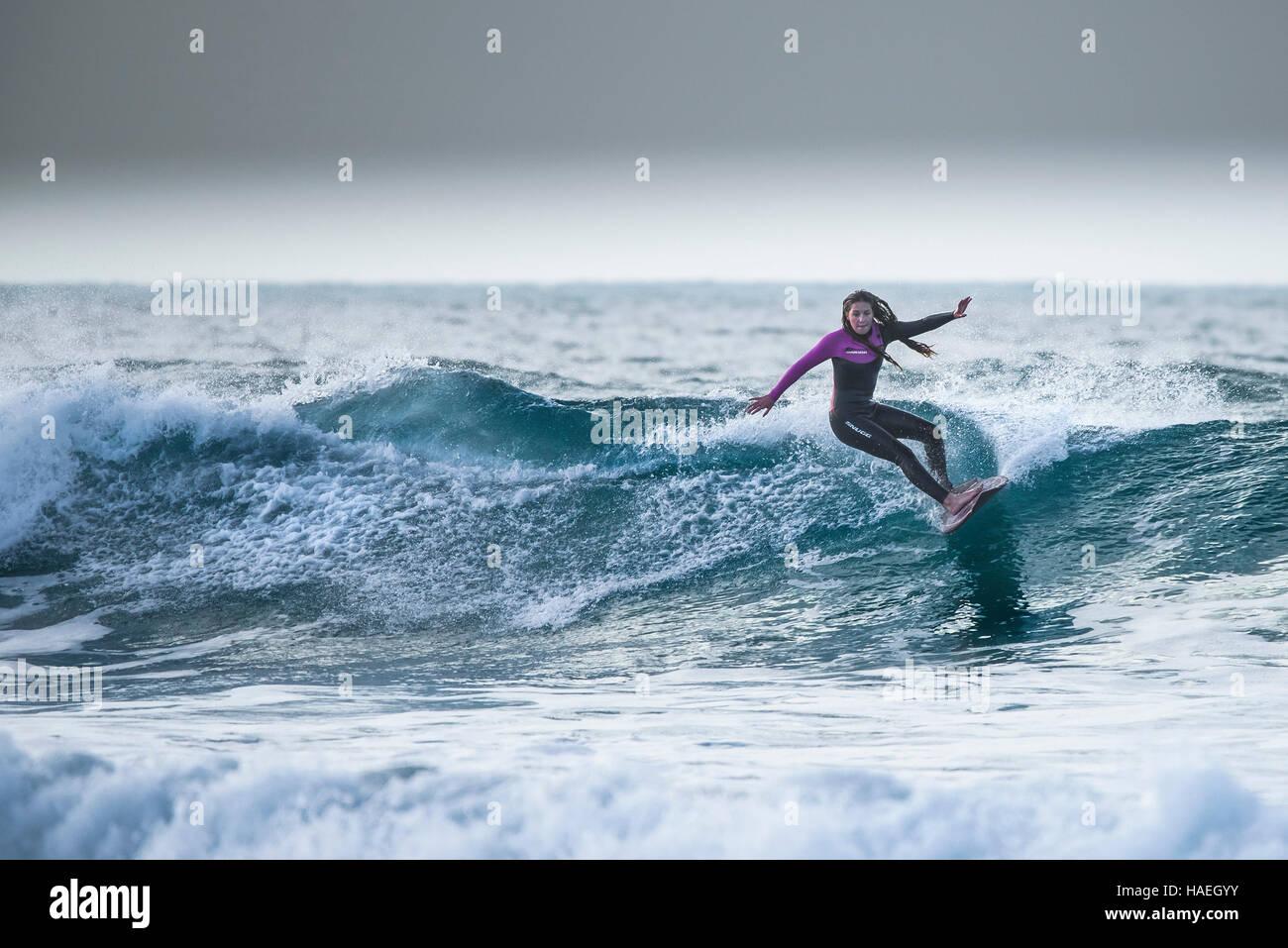A female surfer rides a wave at Fistral in Newquay; Cornwall. UK ...
