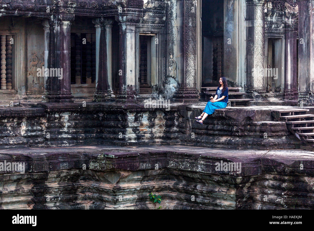 A tourist sits among the massive stone structures at the ancient Angkor ...