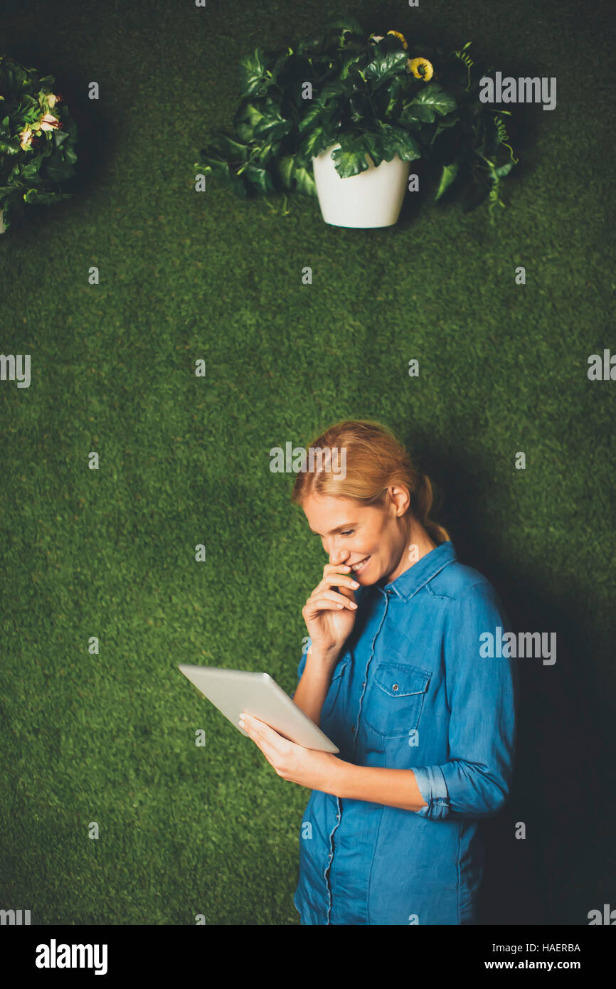 Young woman posing with tablet by green wall Stock Photo - Alamy