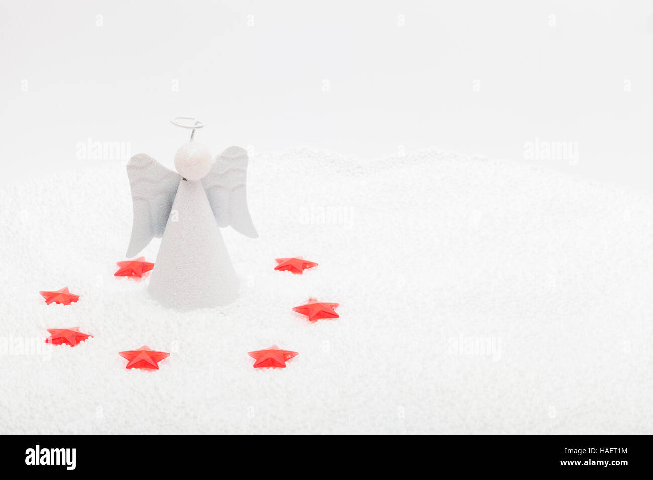 An angel Christmas tree ornament surrounded by plastic stars in ...