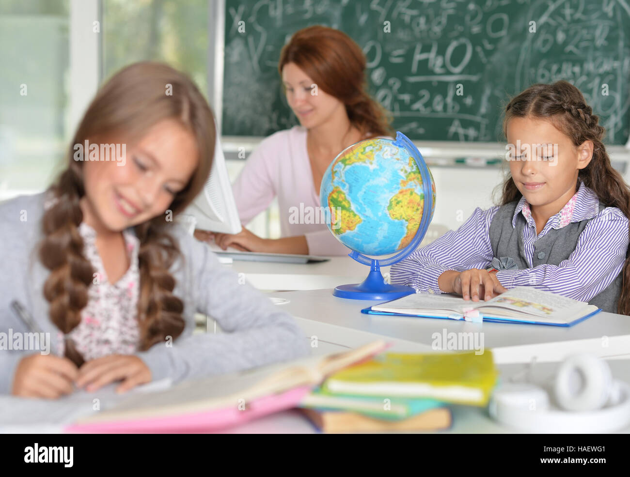 Teacher with two girls at lesson Stock Photo - Alamy