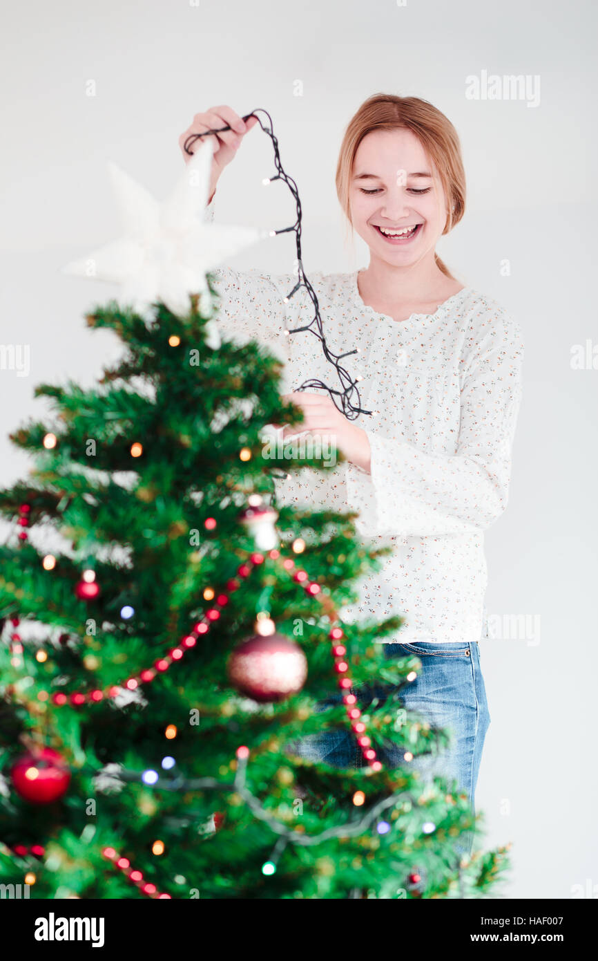 Young girl decorating Christmas tree with lights at home Stock Photo ...