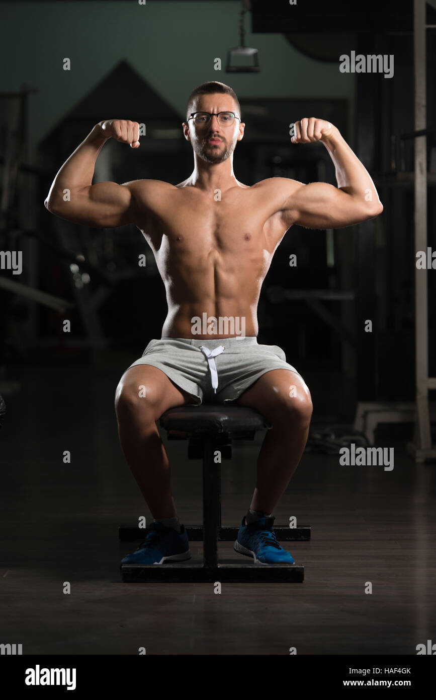 Handsome Geek Man Sitting Strong In The Gym And Flexing Muscles ...