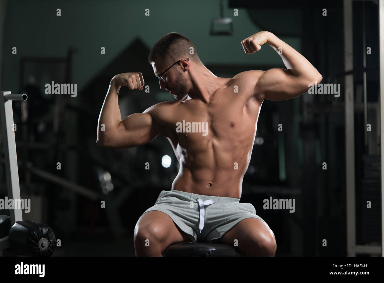 Handsome Geek Man Sitting Strong In The Gym And Flexing Muscles ...