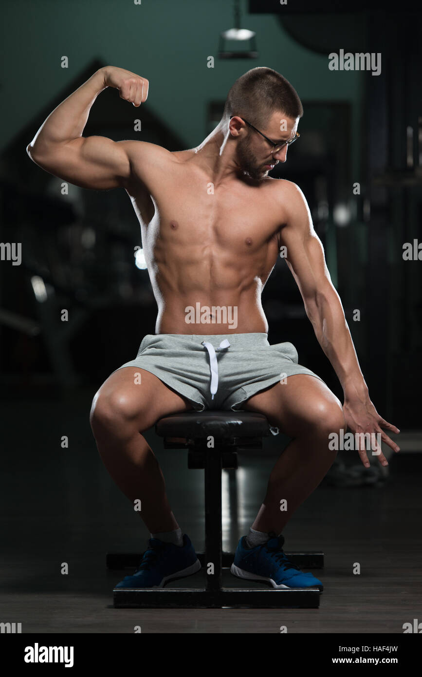 Handsome Geek Man Sitting Strong In The Gym And Flexing Muscles ...