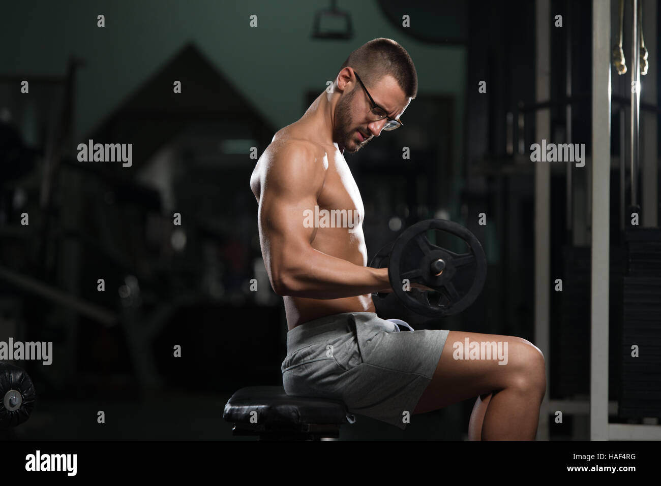 Muscular Nerd Man Doing Heavy Weight Exercise For Biceps With Barbell ...