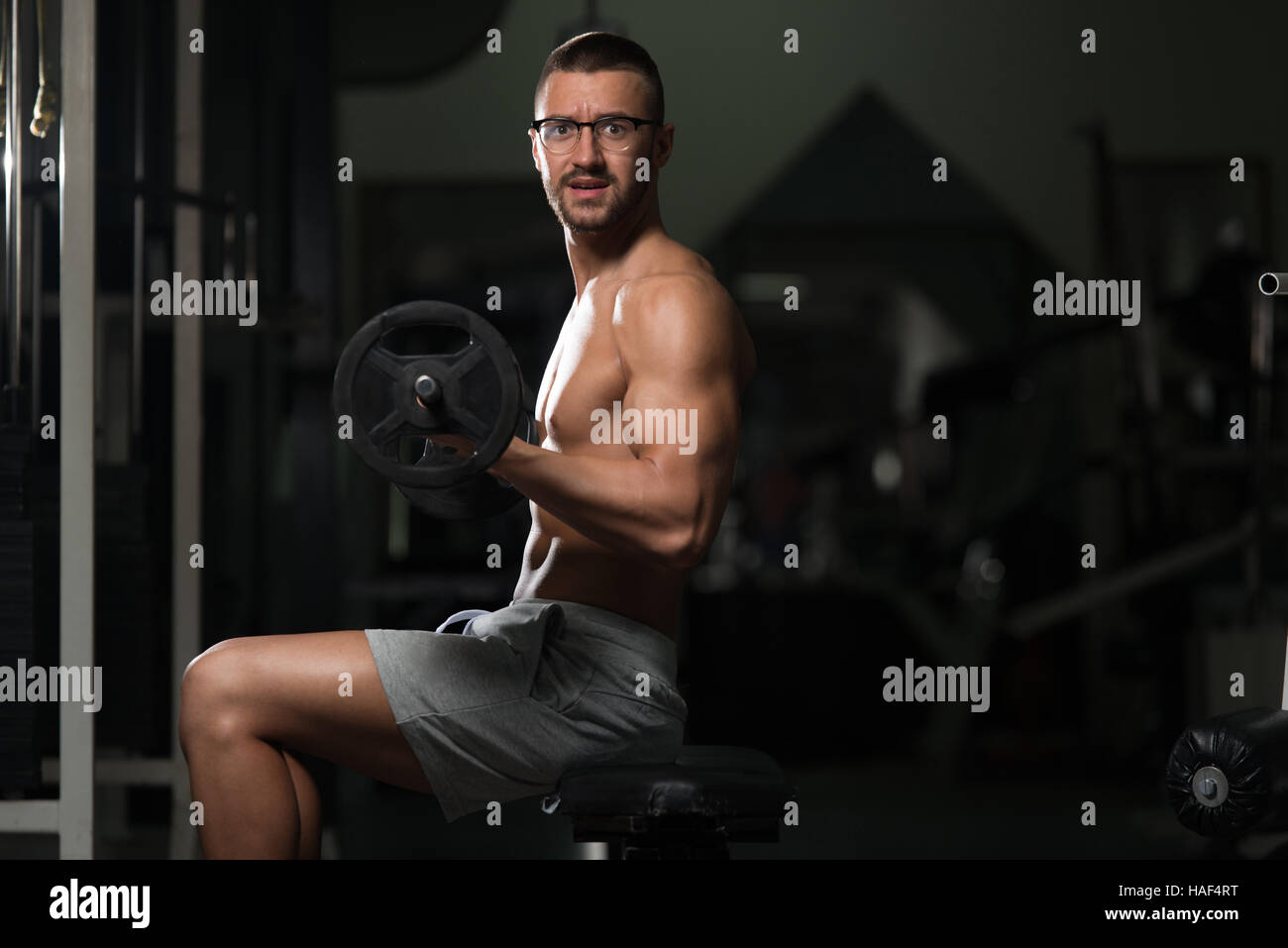 Young Geek Athlete In The Gym Performing Biceps Curls With A Barbell ...