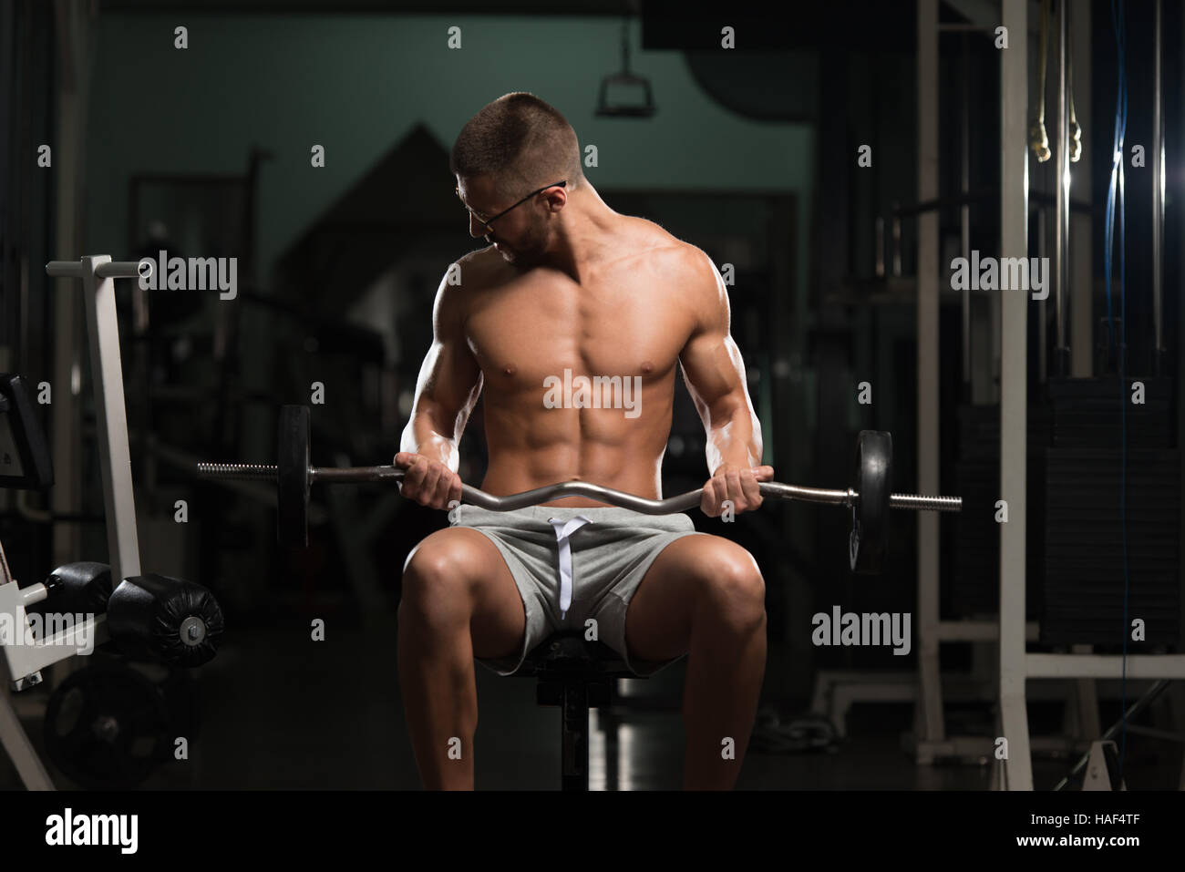 Young Geek Athlete In The Gym Performing Biceps Curls With A Barbell ...
