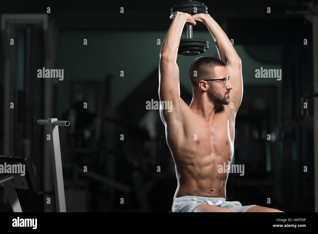 Handsome Man Wearing Glasses Working Out Triceps With Dumbbell In A ...