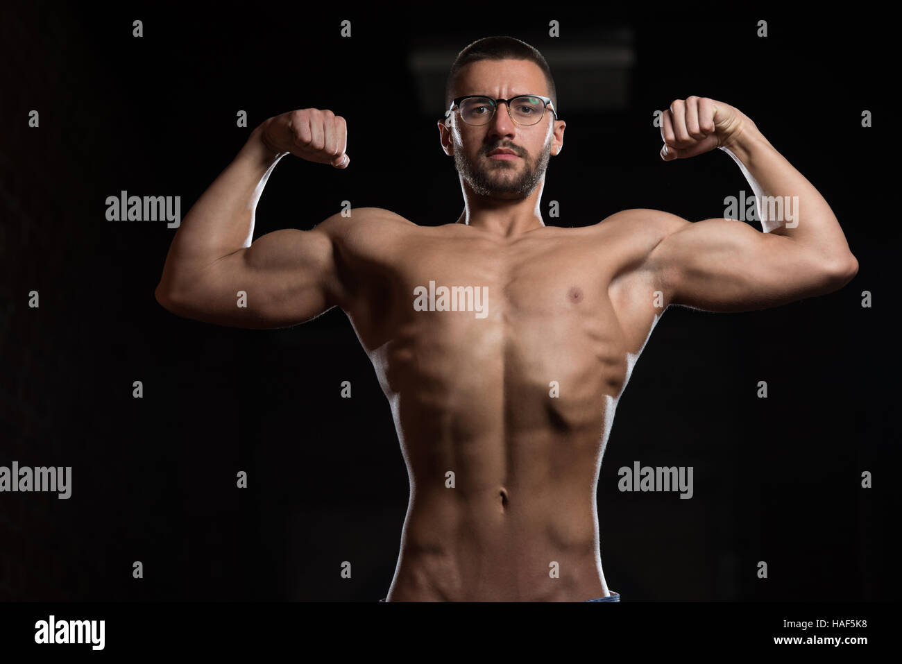 Handsome Geek Man Standing Strong In The Gym And Flexing Muscles ...