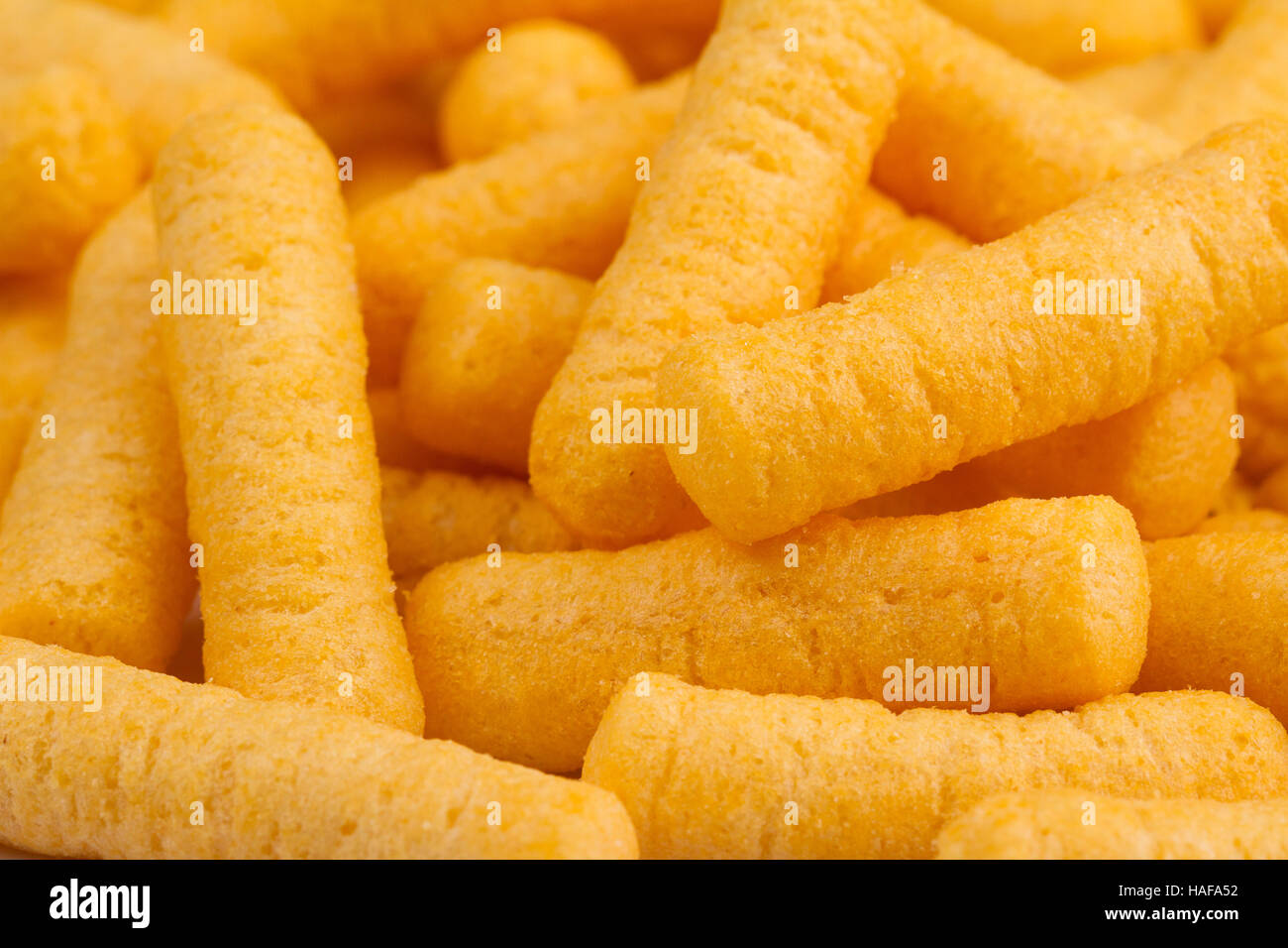 close up detail of many yellow corn puff snacks isolated on white ...