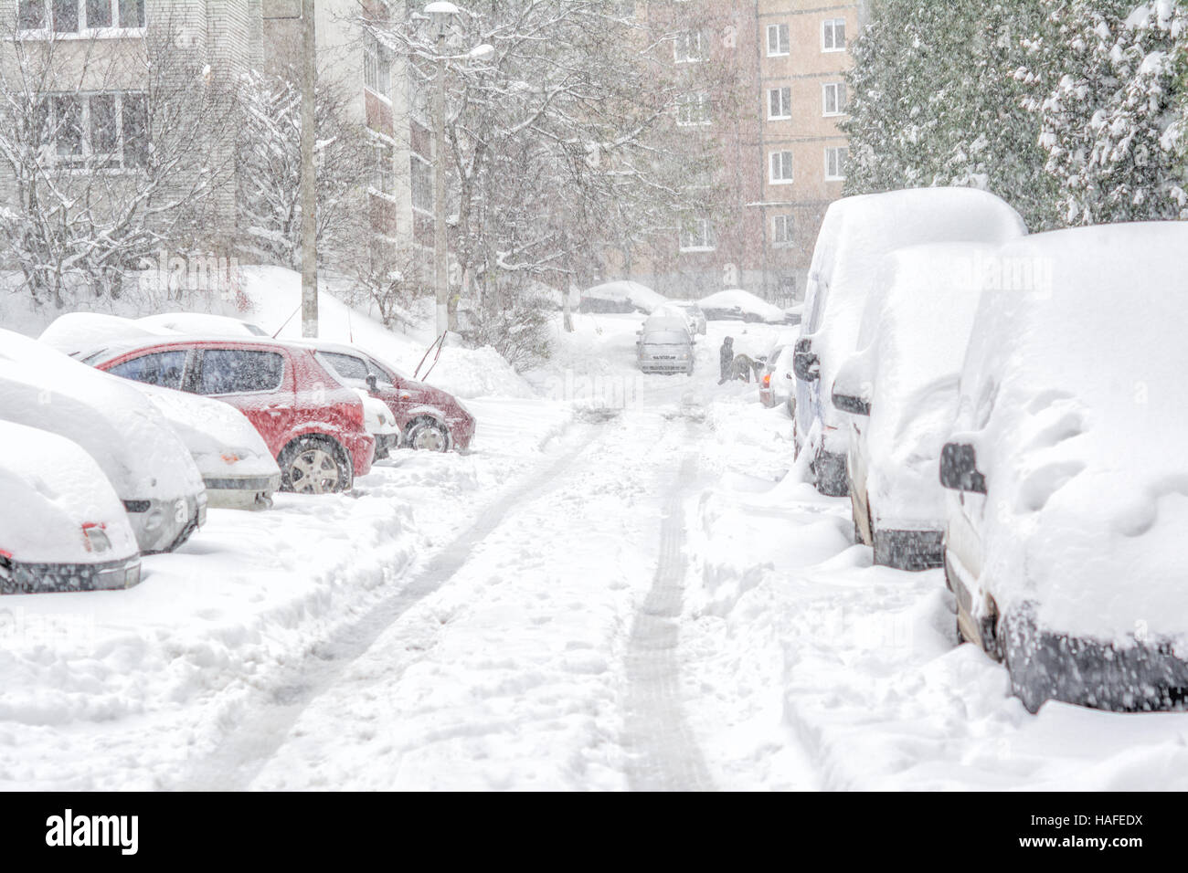 Snowstorm, snow-covered street and cars with a lonely pedestrian Stock ...
