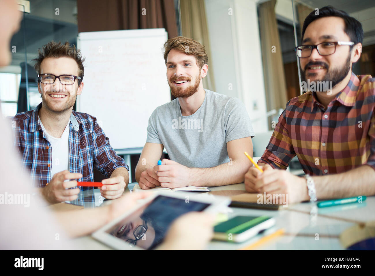 Three designers listening to one of colleagues Stock Photo - Alamy