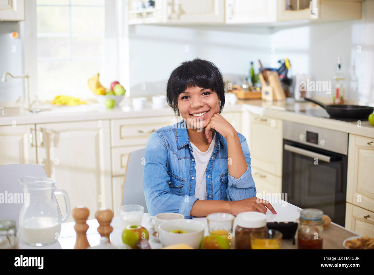 Pretty woman sitting by table in the kitchen at home Stock Photo - Alamy