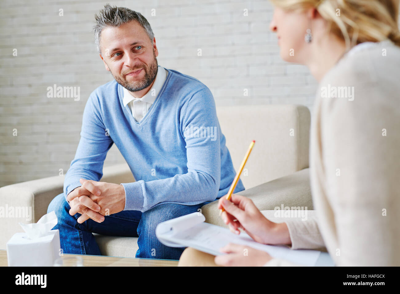 Happy man looking at his psychologist during talk Stock Photo - Alamy