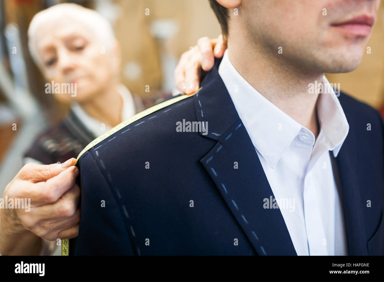 Tailor measuring shoulder length of male jacket Stock Photo - Alamy