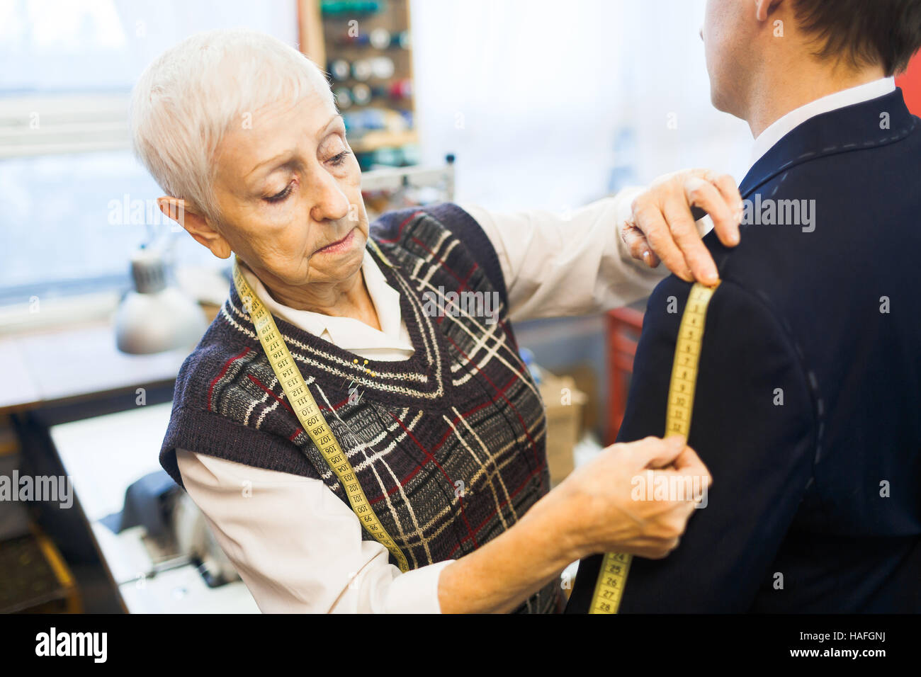 Experienced tailor measuring length of jacket sleeve Stock Photo - Alamy