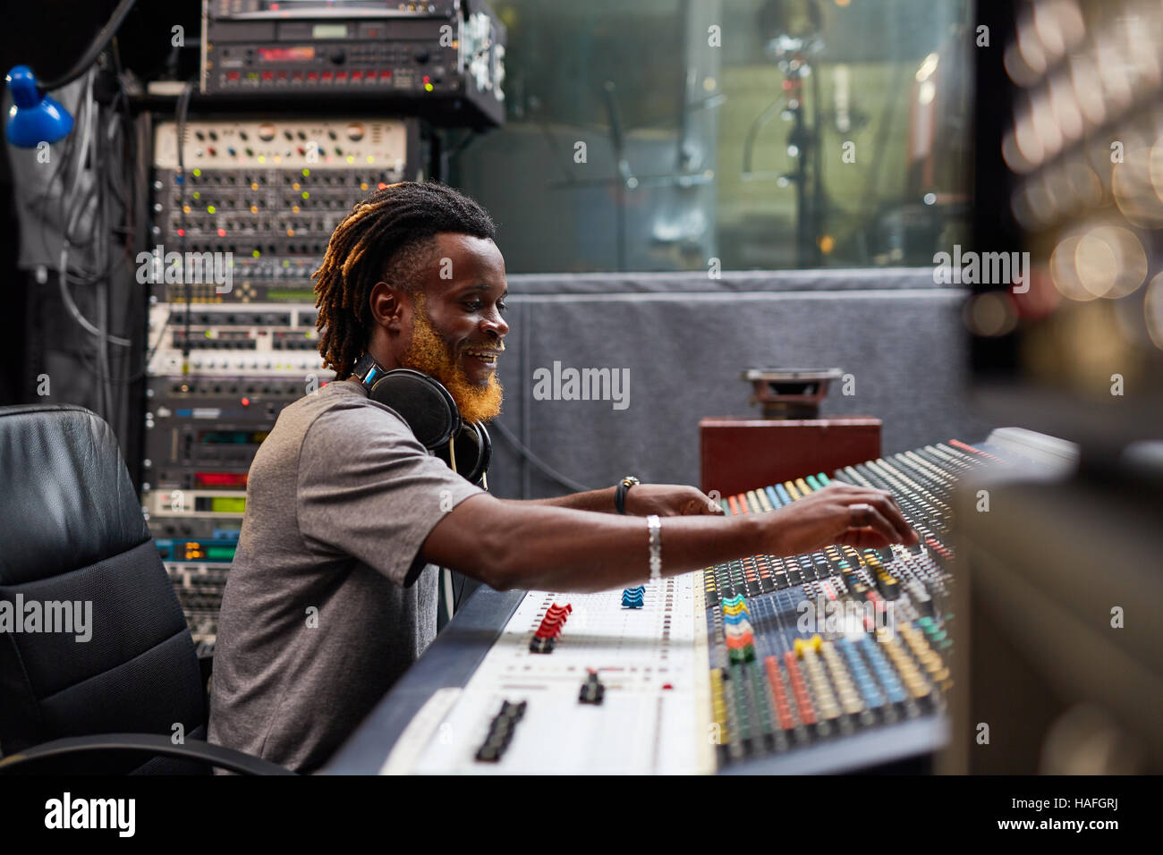 Young sound-operator sitting by soundboard in audio studio Stock Photo ...