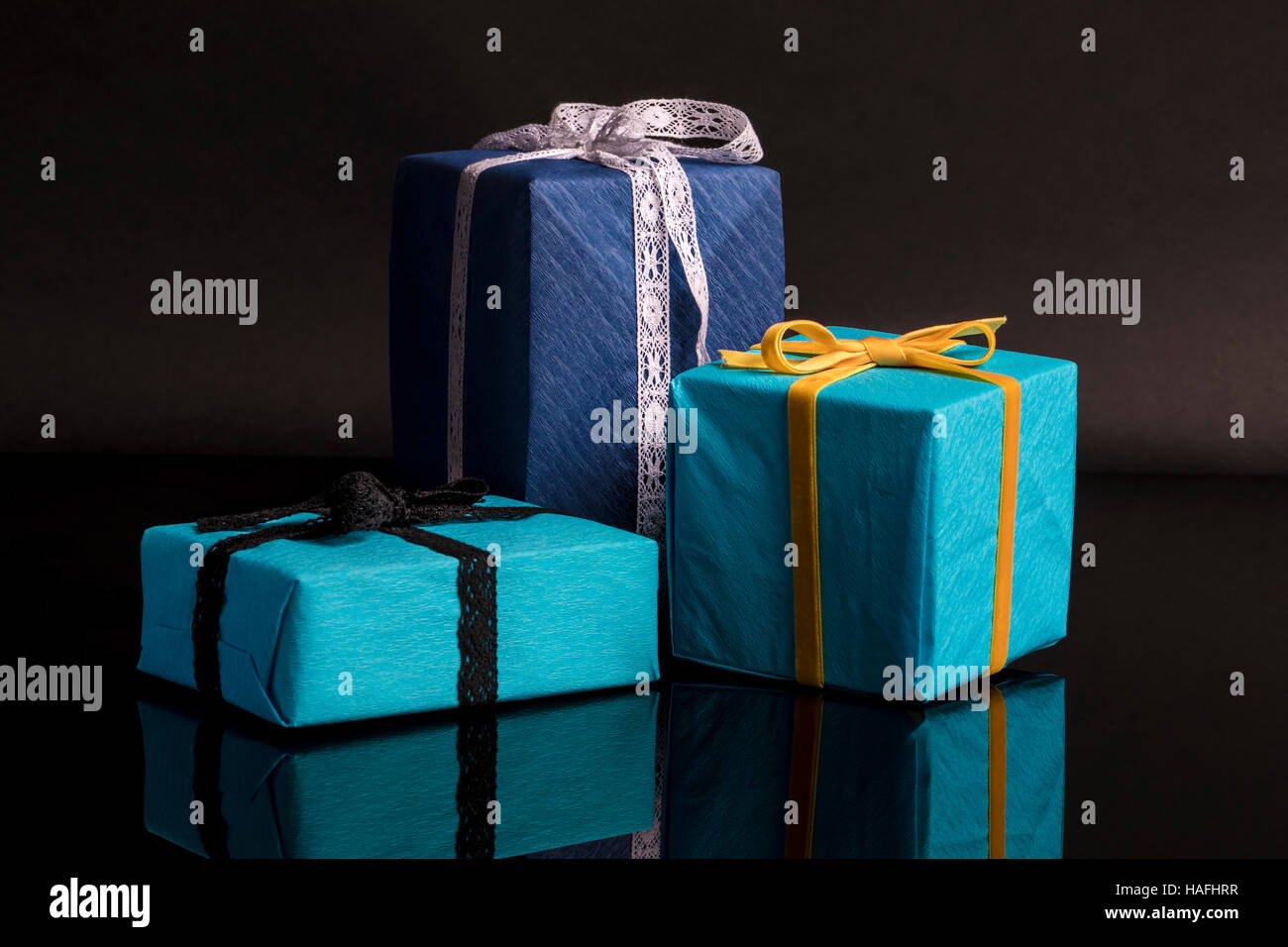 Three presents of different sizes wrapped in blue and turquoise ...