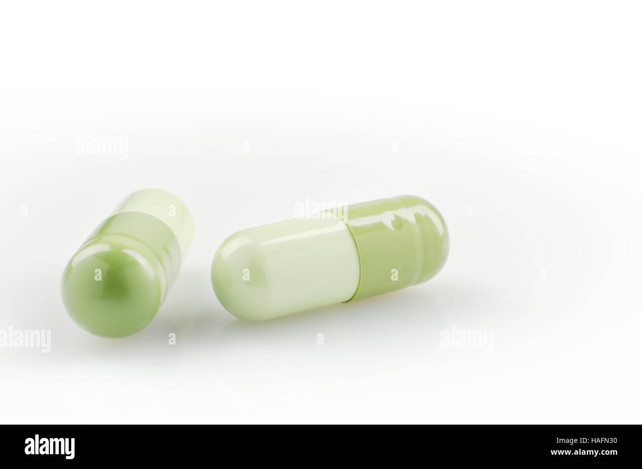 Medical theme. Bright green capsules on the white surface. Closeup ...