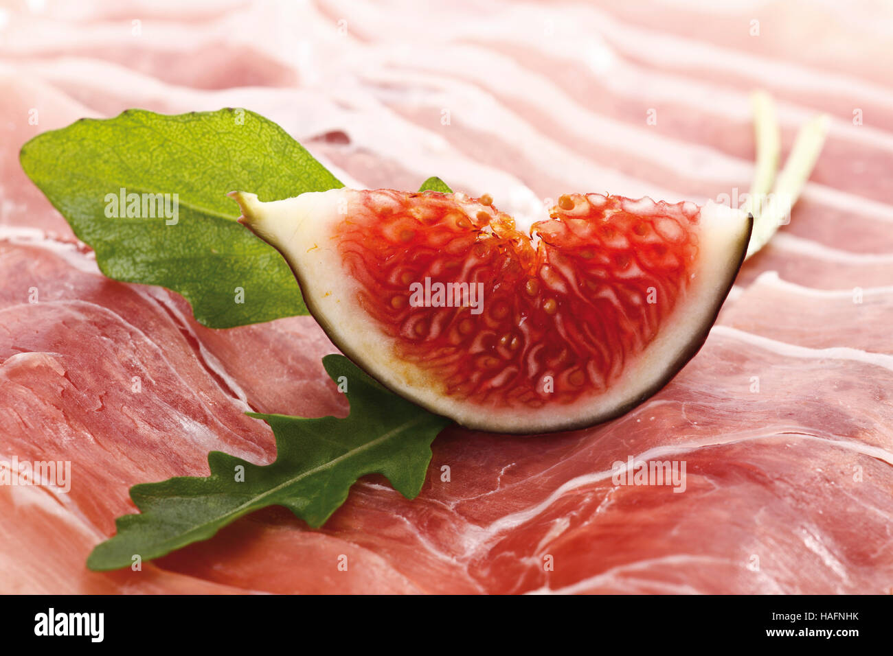 Fresh fig on raw ham garnished with rucola leaves Stock Photo - Alamy