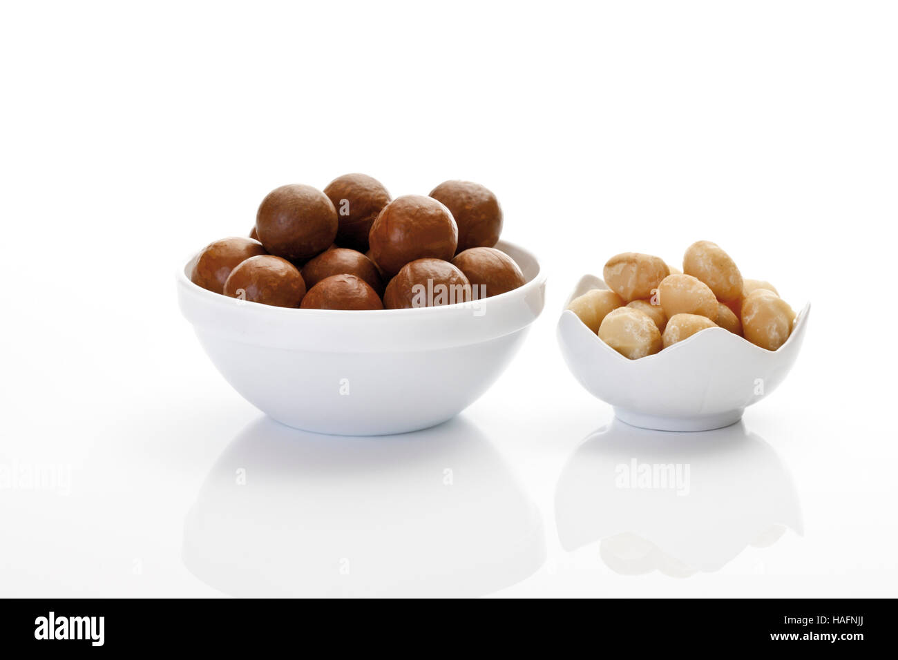 Un-shelled macadamia nuts and shelled macadamia kernels in porcelain ...