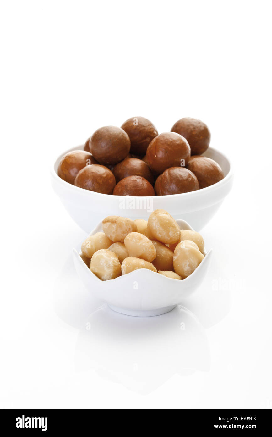 Un-shelled macadamia nuts and shelled macadamia kernels in porcelain ...