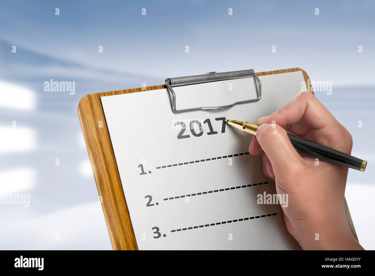 Woman write with pen on the paper over blur background. 2017 to do list ...