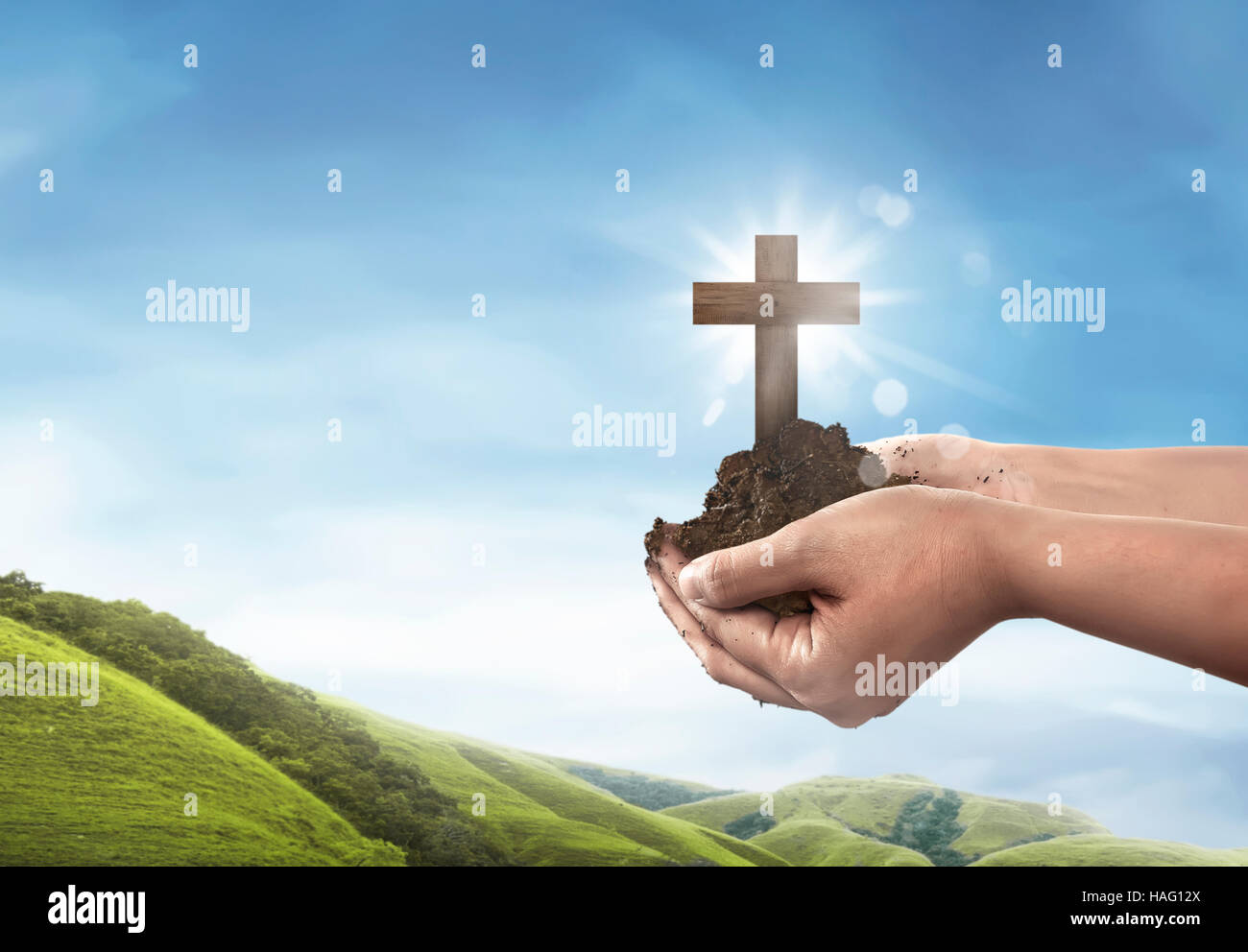 Human hand holding christian cross with soil on the hand over blue sky ...