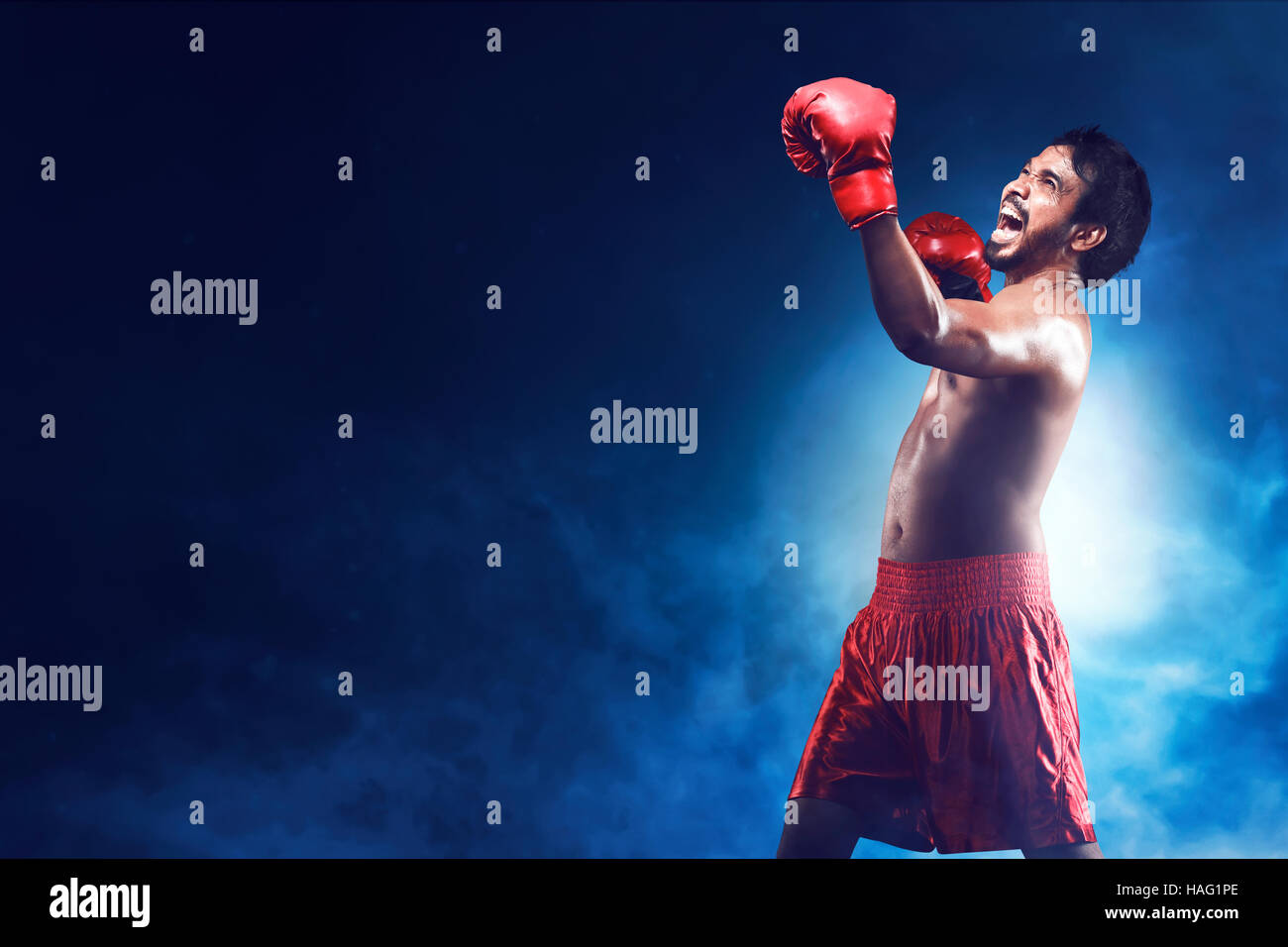 Portrait of happiness asian boxer man standing against blue background ...