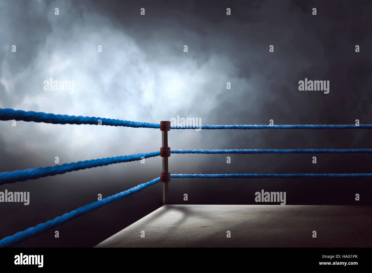 View of a regular boxing ring surrounded by blue ropes spotlit by a ...