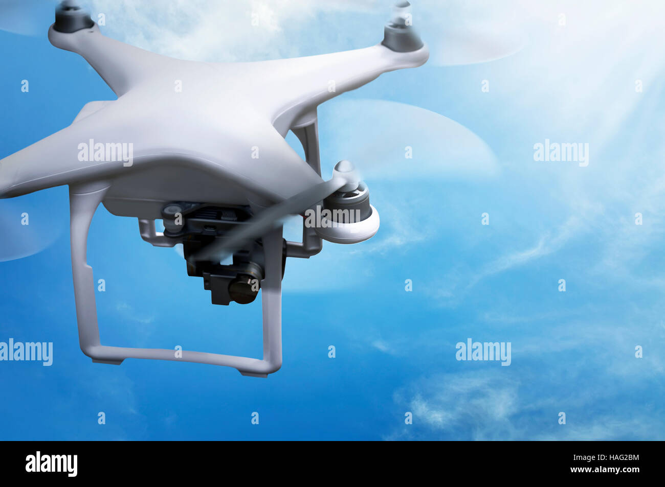 Small white drone flying with blue sky background Stock Photo - Alamy