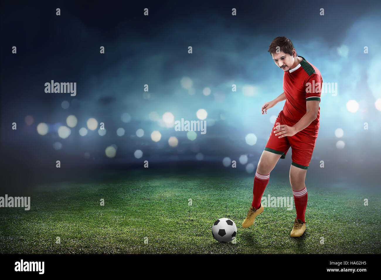 Asian football player kick ball on the stadium Stock Photo - Alamy