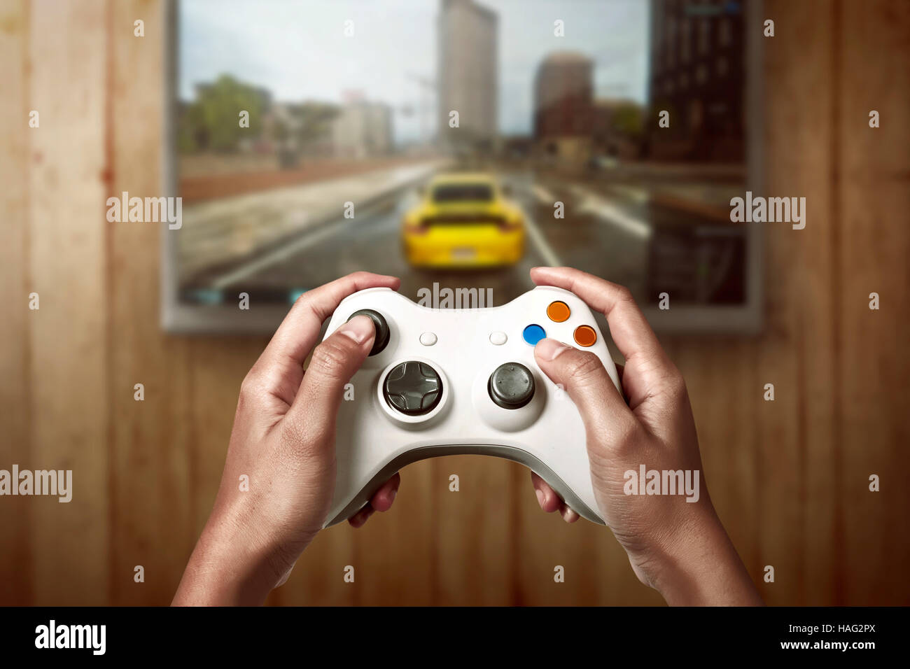 Hand holding game console controller playing racing game on the ...