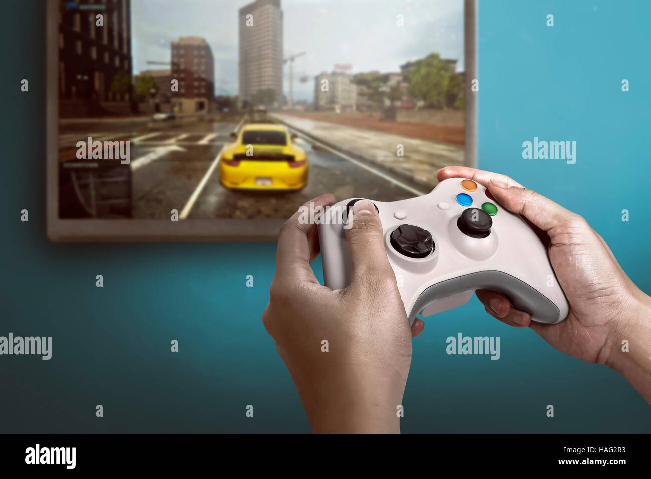 Hand holding game console controller playing racing game on the ...