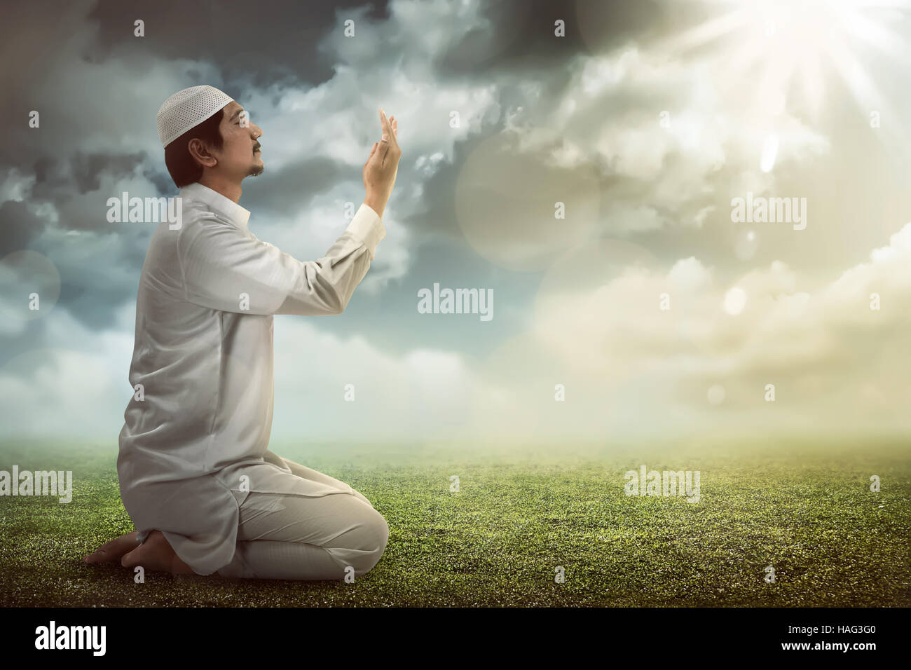 Young muslim man praying on the green grass field Stock Photo - Alamy