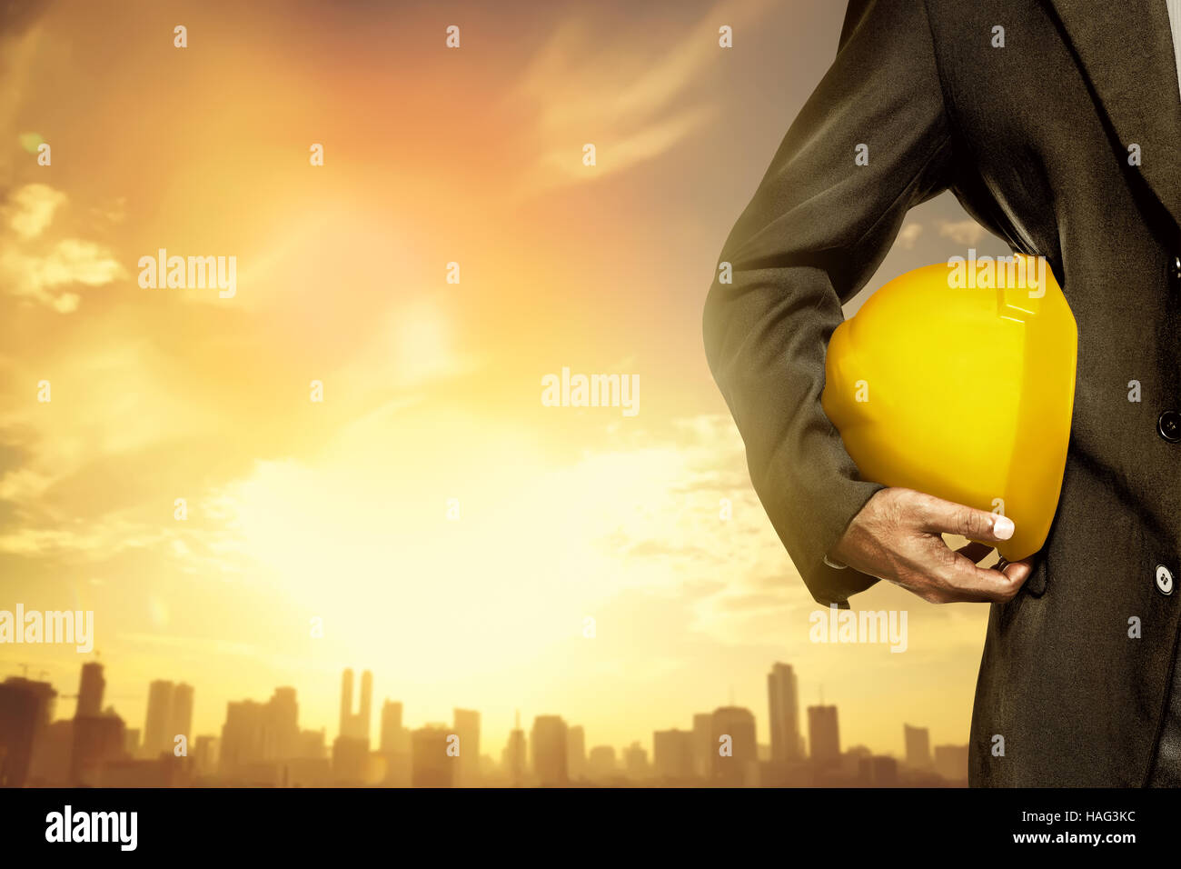 Hand or arm of engineer hold yellow plastic helmet for worker. Labor ...