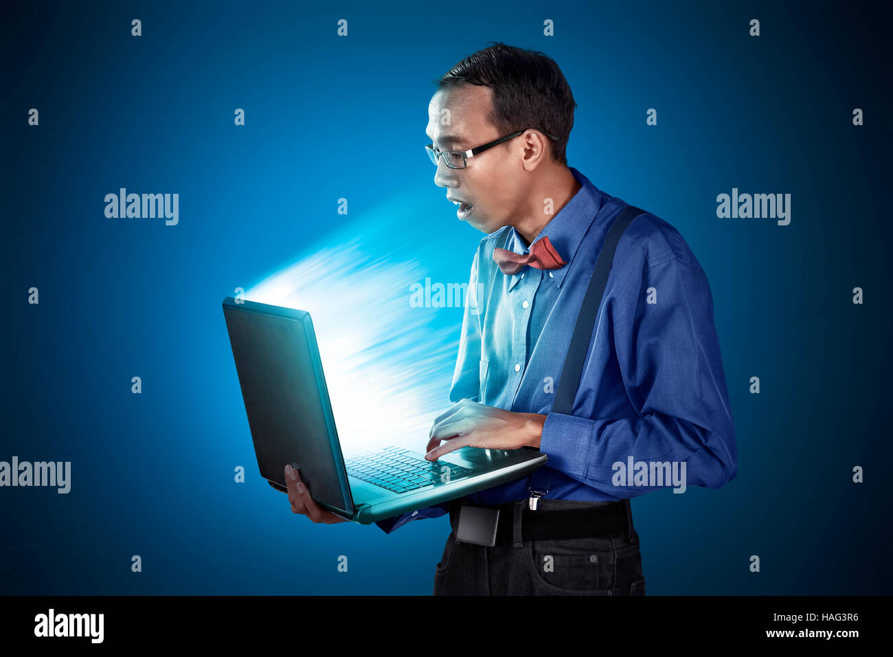 Nerdy man use laptop with standing position, gawk face and looks like ...