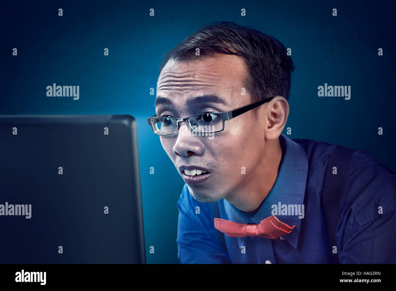 Nerd man concentration using laptop, eyes bulging and looks very geeky ...