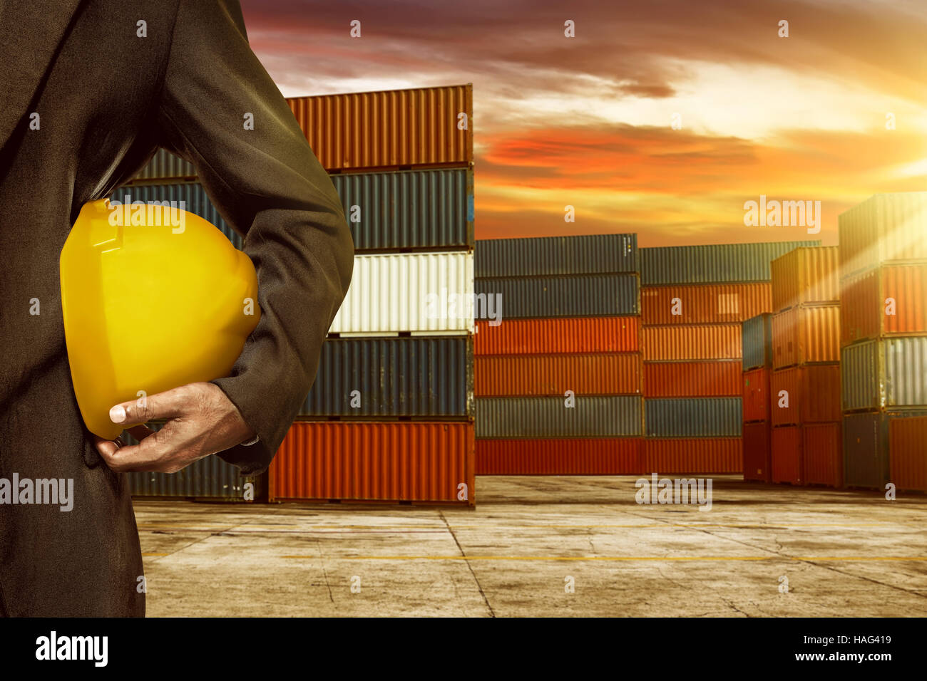 Woman hand holding yellow helmet in the port with container background ...