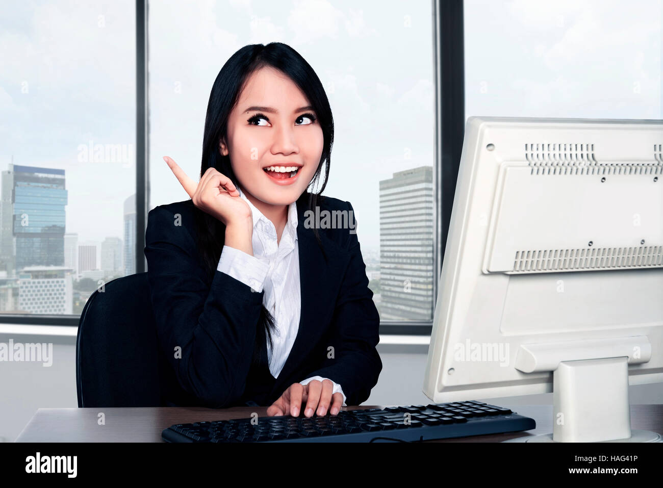 Smiling happy woman using computer with office background Stock Photo ...