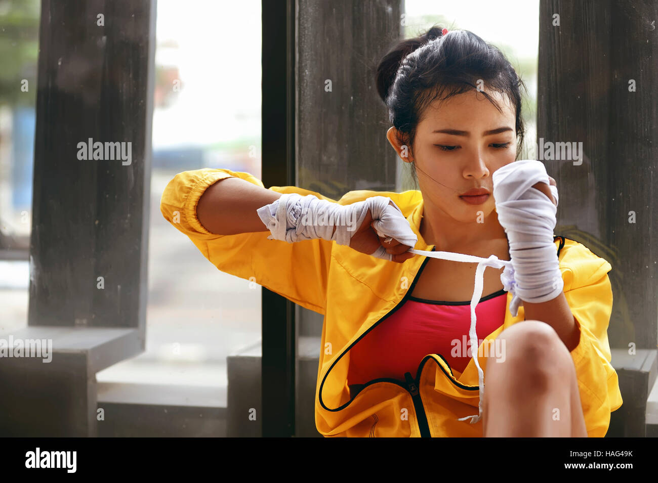 Beauty asian woman in yellow jacket wraps her wrist with white sports ...