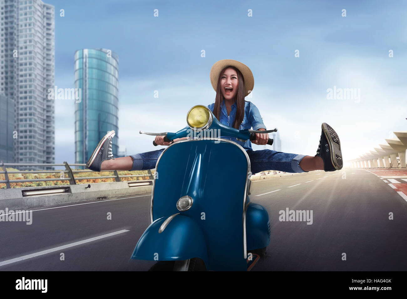 Beautiful happy asian woman riding a scooter raising both legs on the ...